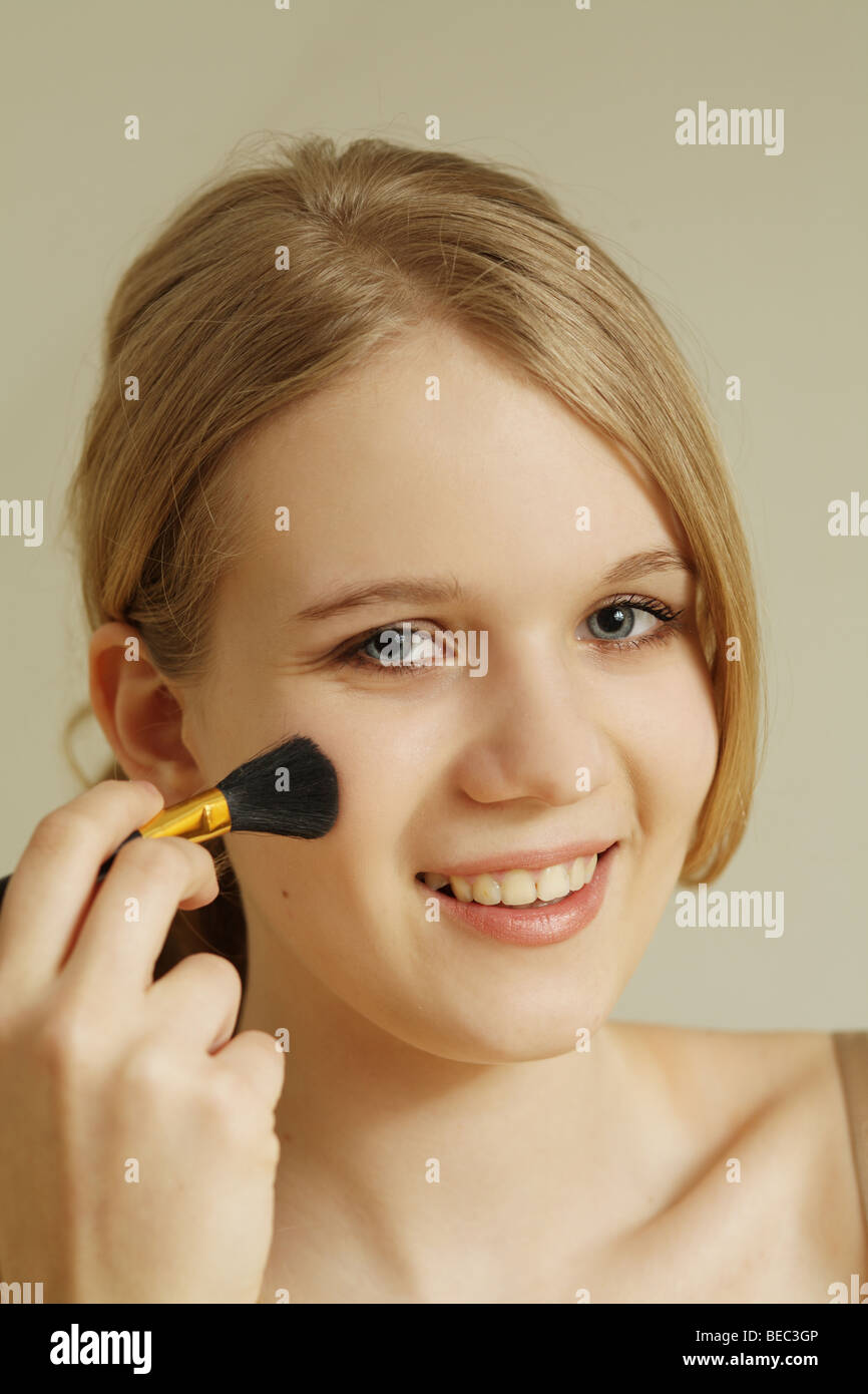 Teenage girl applying face powder with brush Stock Photo - Alamy