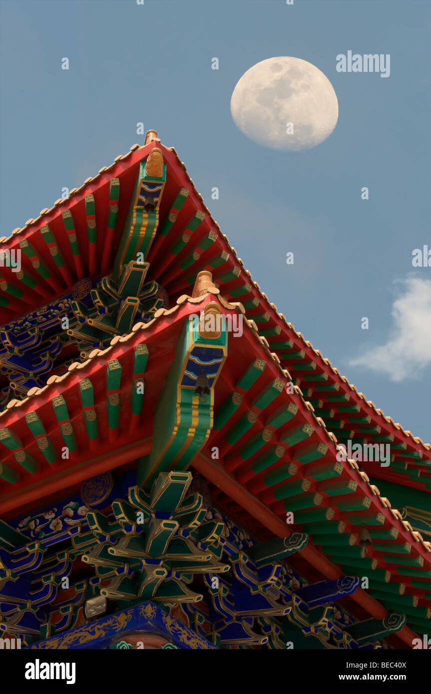 The moon shown in the daytime sky behind the eaves of a Chinese temple ...
