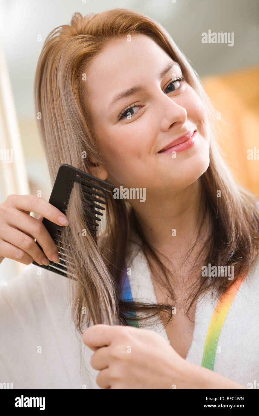 Young woman brushing hair in the bathroom Stock Photo - Alamy