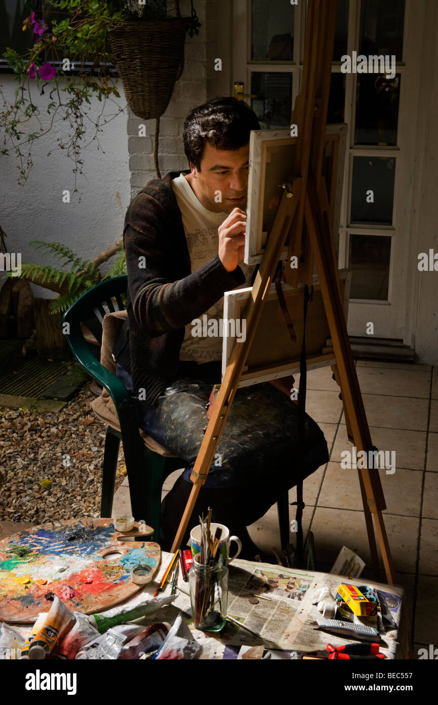 An artist painting with oils on canvas on an easel in his studio at St ...