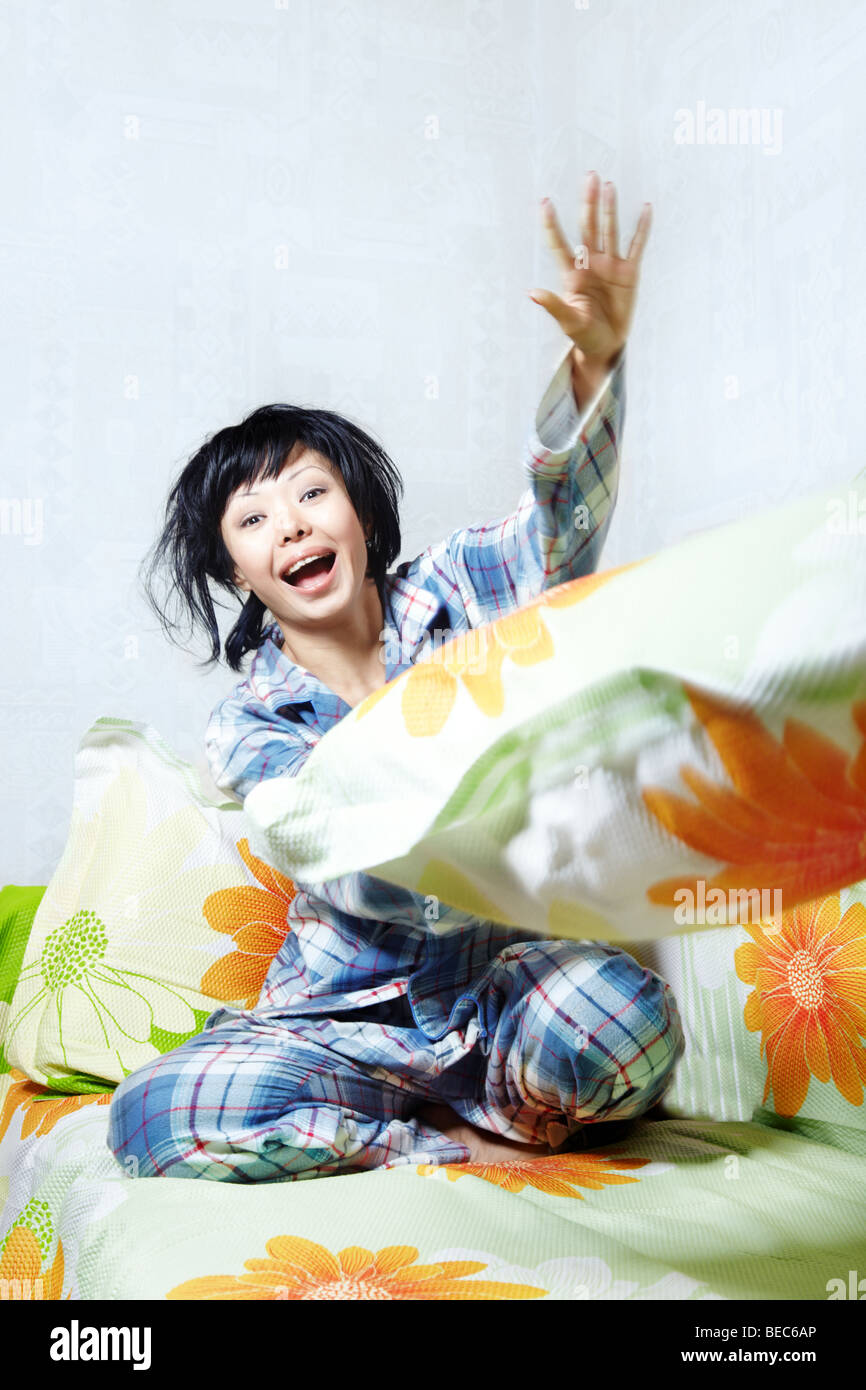 Laughing lady in pajamas playing with pillow Stock Photo - Alamy