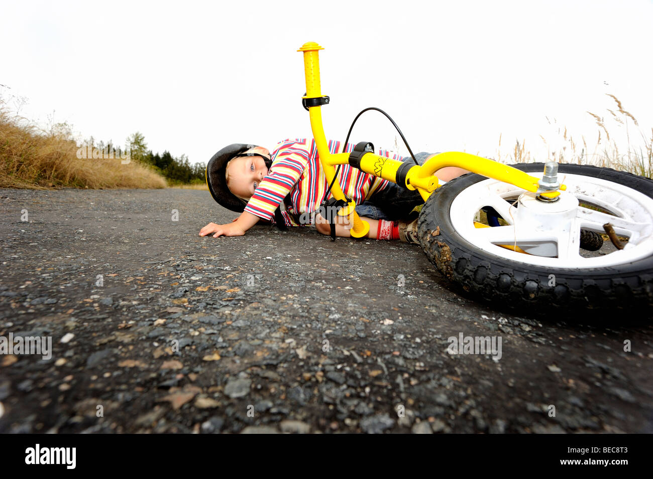 Child boy cycling bicycle on the country road with bike helmet, falling ...
