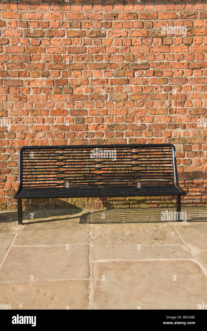 Metal bench against brick wall Stock Photo - Alamy