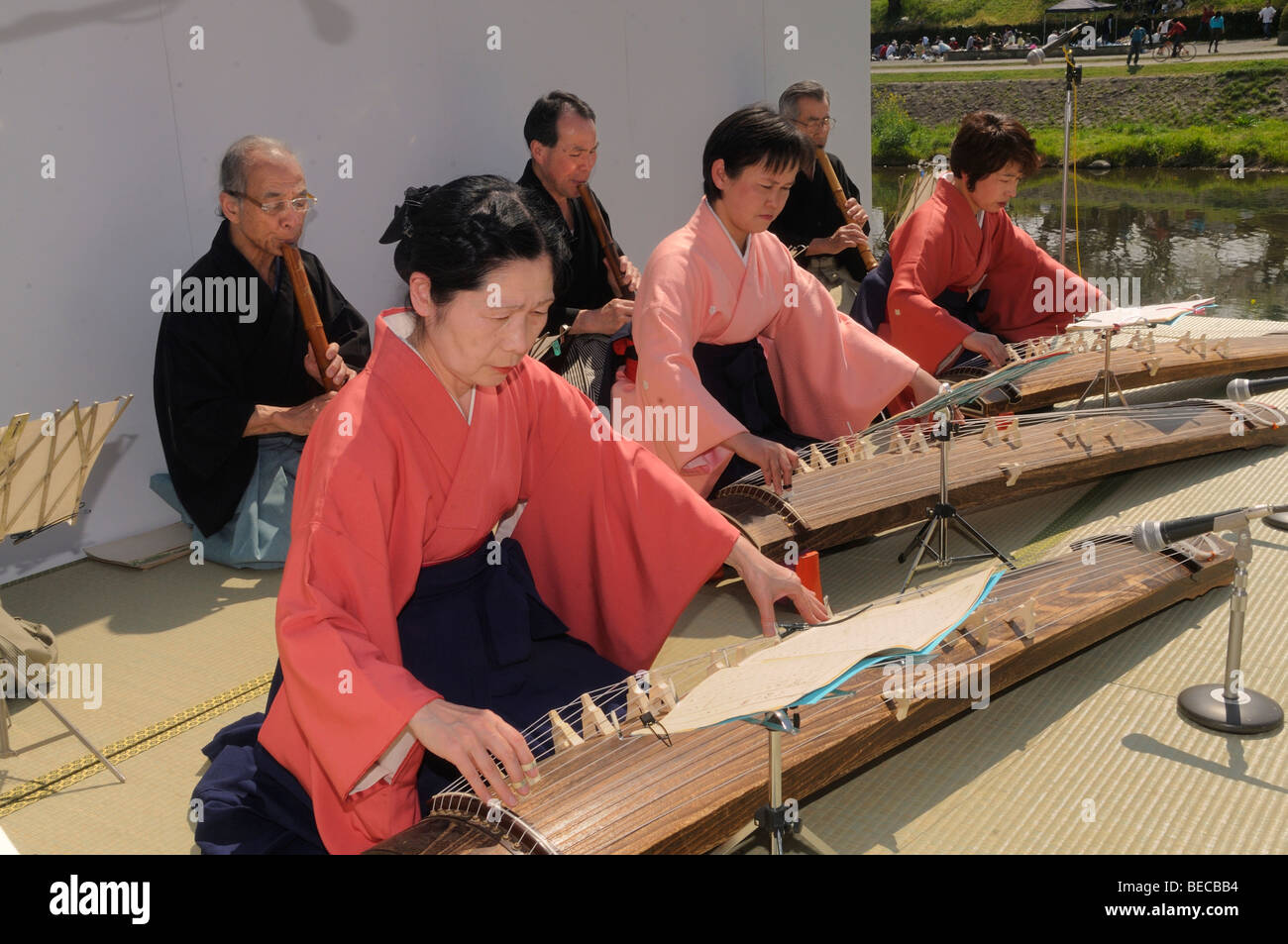 Japanese women playing Kodo zithers outdoors on the banks of the Kamo ...