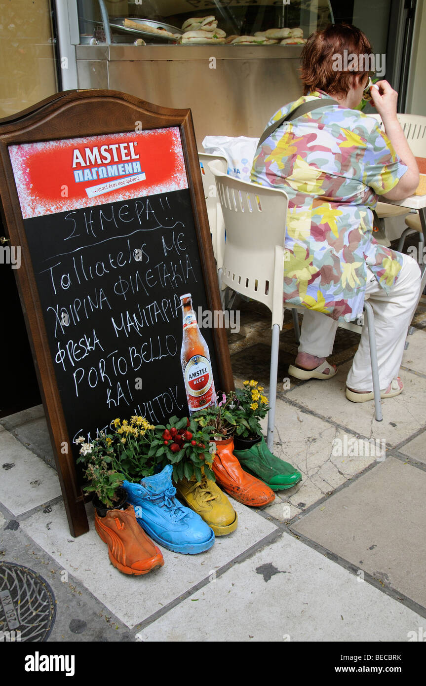 Pavement cafe decorated menu board and shoes filled with flowering ...