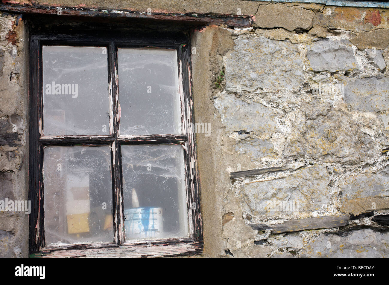 Cobweb covered glass window with peeling paint on the frame against a ...
