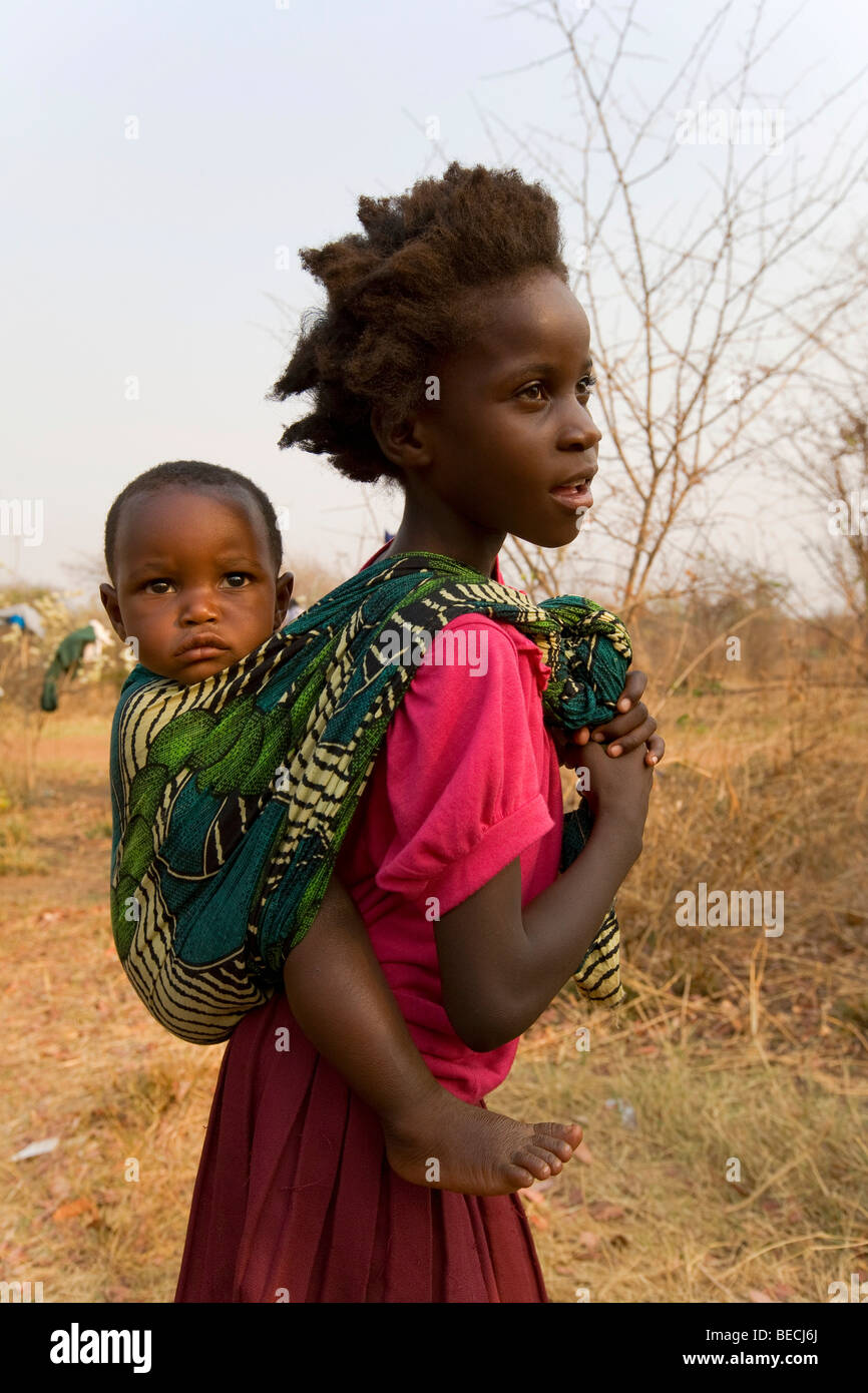 Child carrying an infant in a cloth, African village Sambona, Southern ...