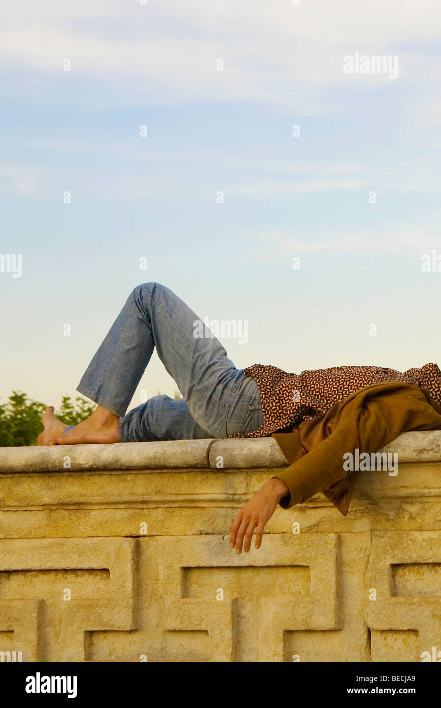 Side profile of a young man lying on a stone wall Stock Photo - Alamy