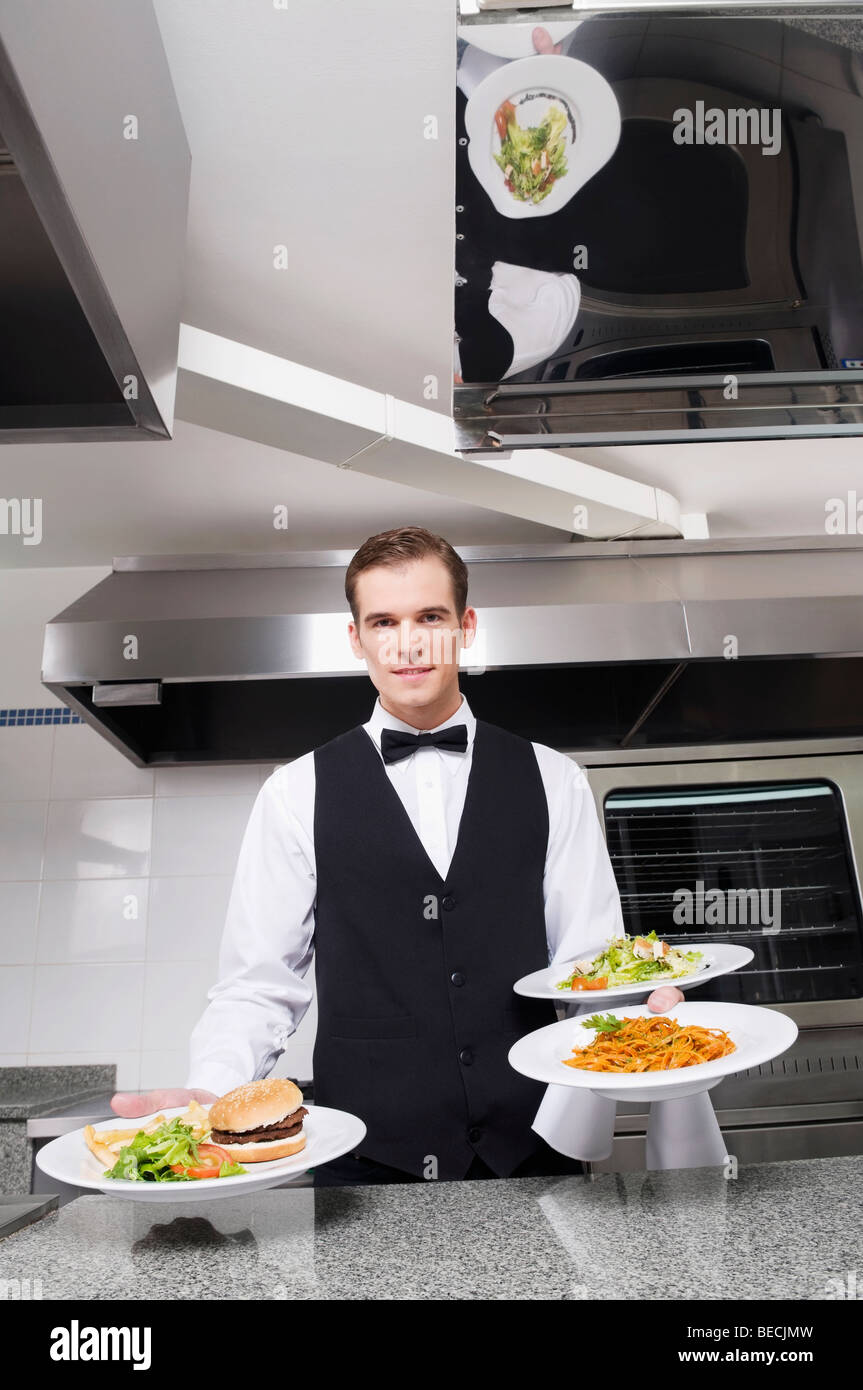 Waiter holding plates of foods and smiling Stock Photo - Alamy