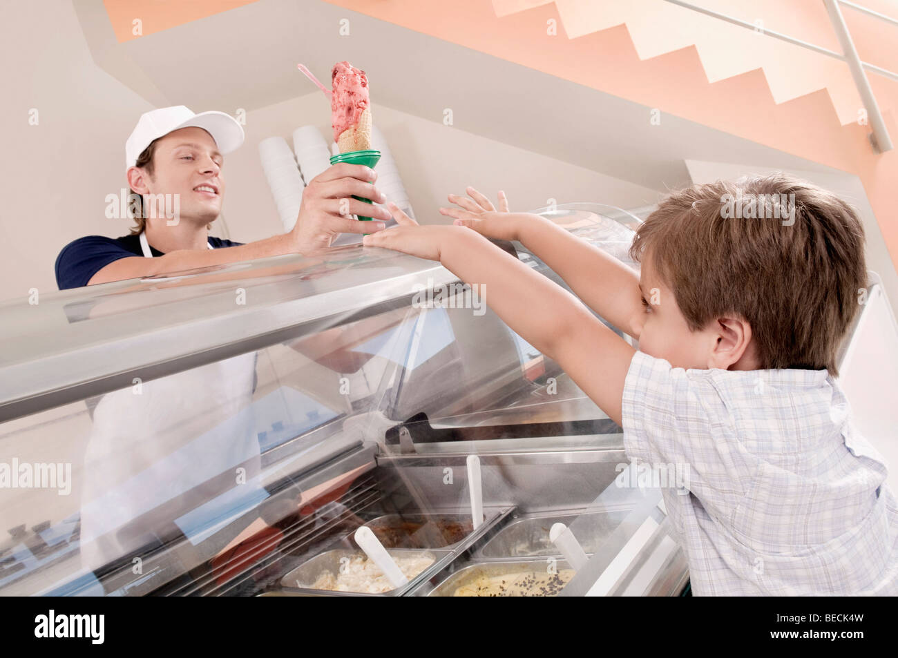 Sales clerk giving ice cream to a boy in an ice cream parlor Stock ...