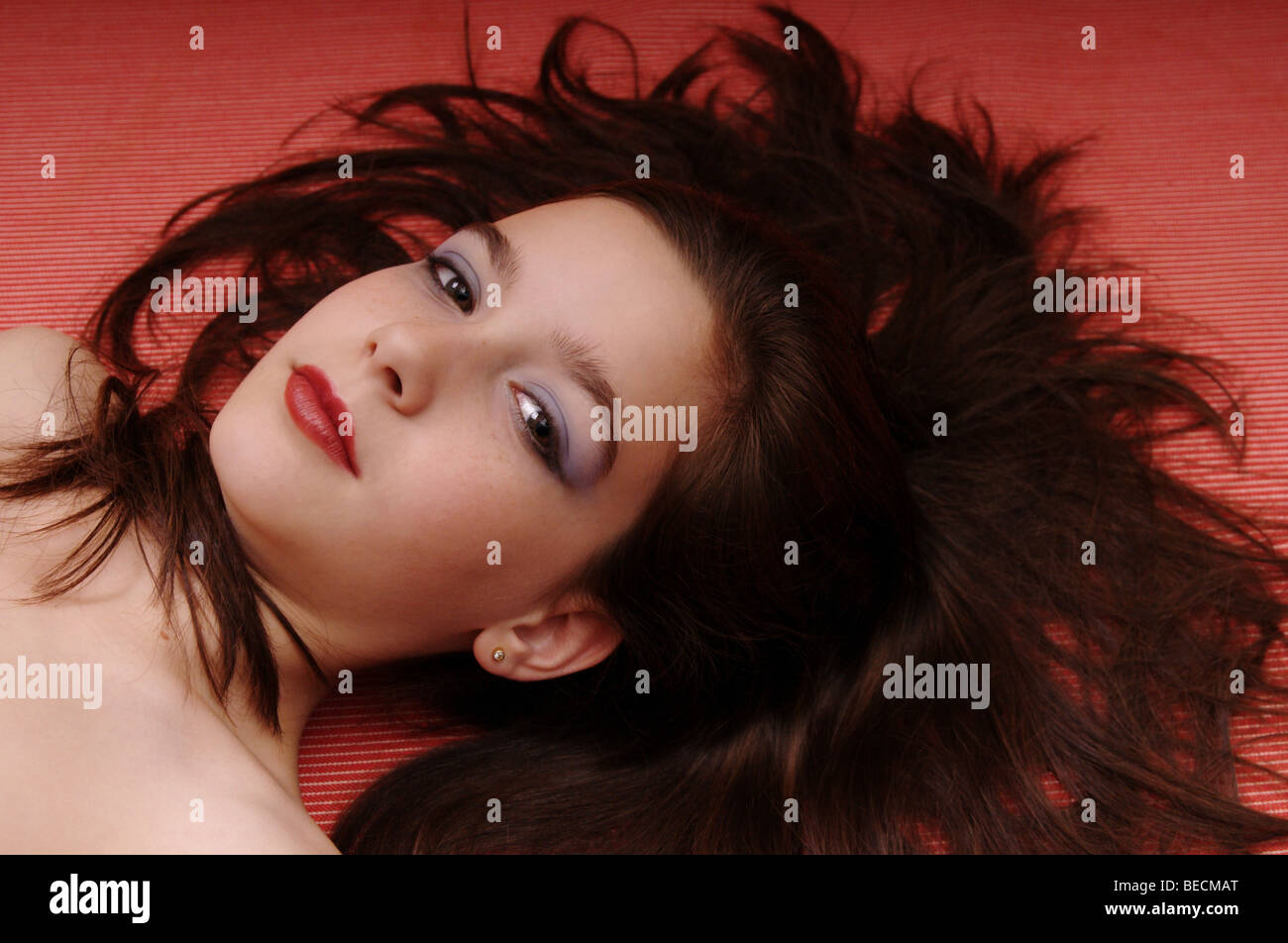 Young girl with long brown hair laying down and making eye contact ...