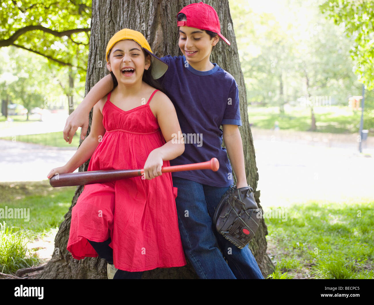Smiling mixed race brother and sister holding baseball bat and mitt ...