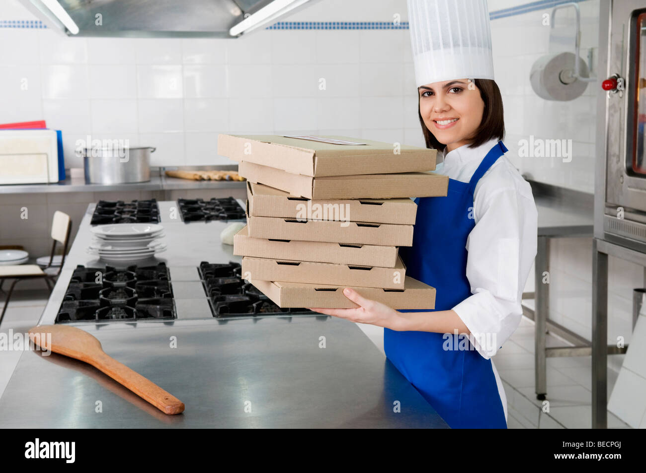Female chef holding stack of pizza boxes and smiling Stock Photo - Alamy