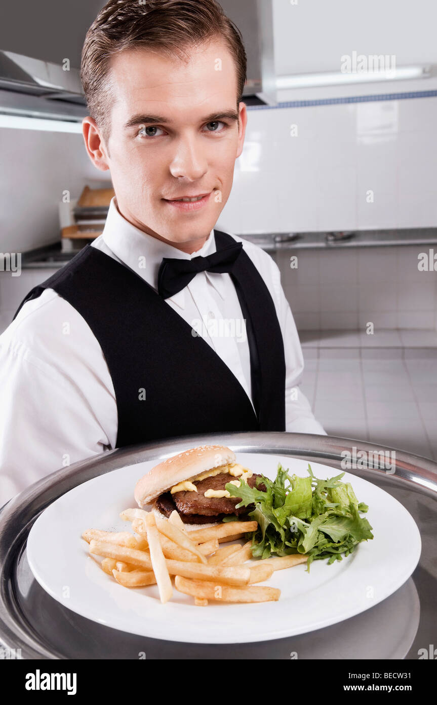 Portrait of a waiter holding a tray of snacks Stock Photo - Alamy