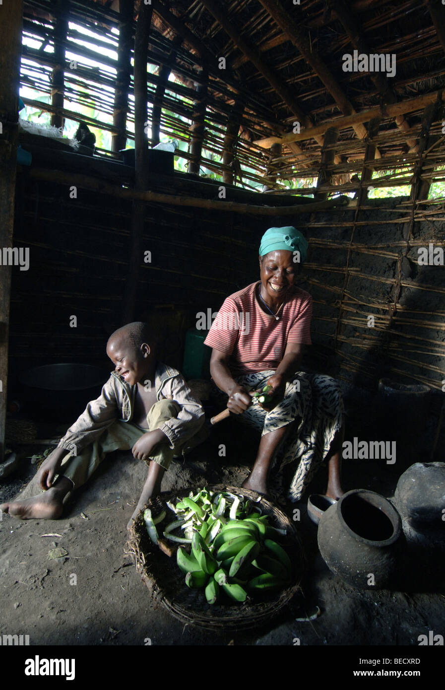 Bakonzo mother and son cooking in mud hut kitchen, Rwenzori Mountains ...