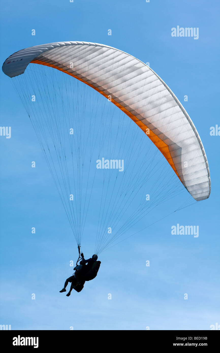 Two paraglider tandem fly against blue sky. Tandem paragliding flight ...