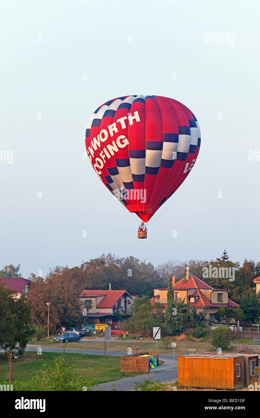 Colorful hot air balloon floating over a residential area at dawn Stock ...