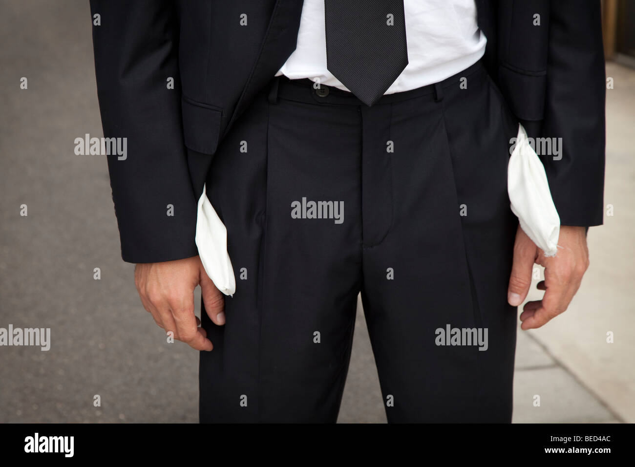 midsection of a businessman`s suit showing pulled out empty pockets ...