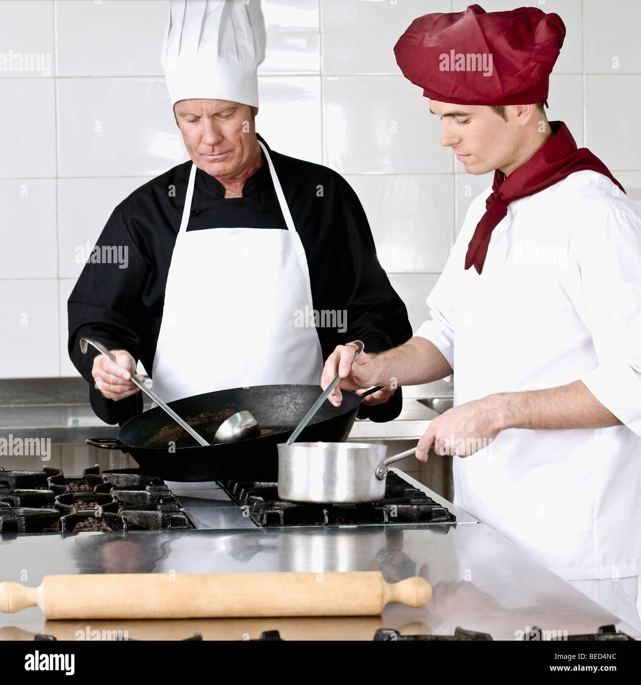Two chefs cooking food in the kitchen Stock Photo - Alamy