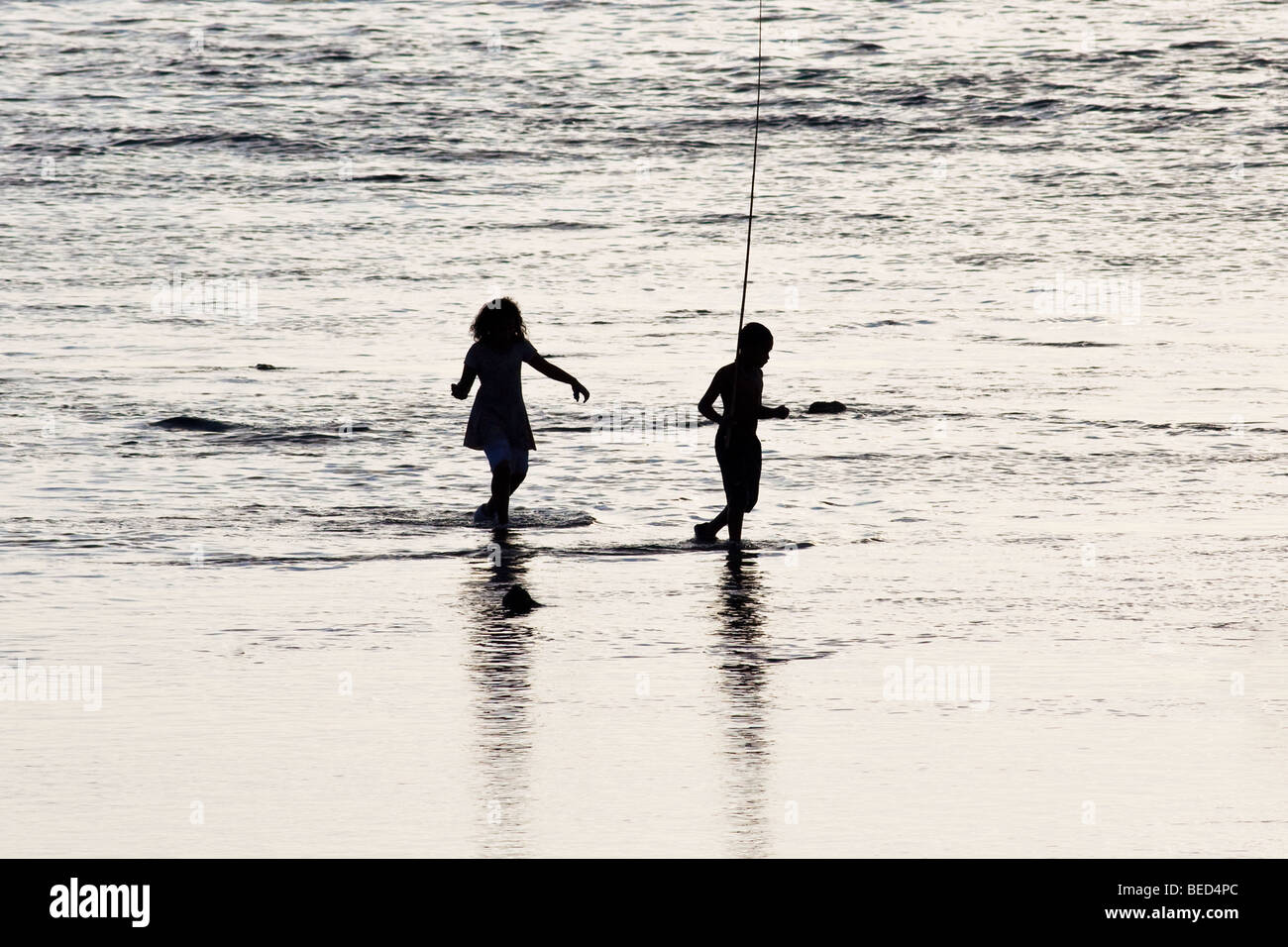 Local children fishing in shallow waters at sunset in The Cook Islands ...