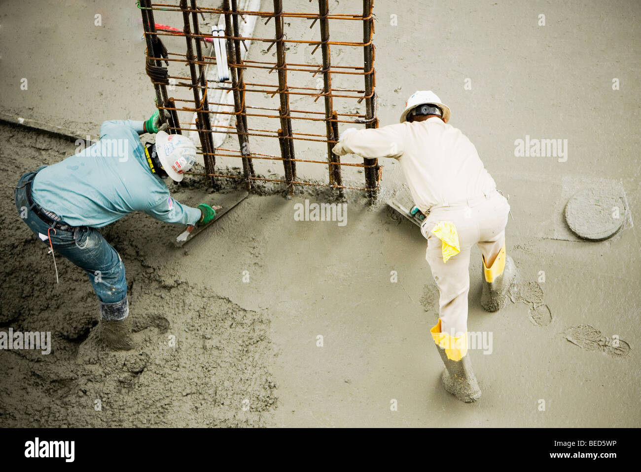 Rear view of two construction workers working at construction site hi ...