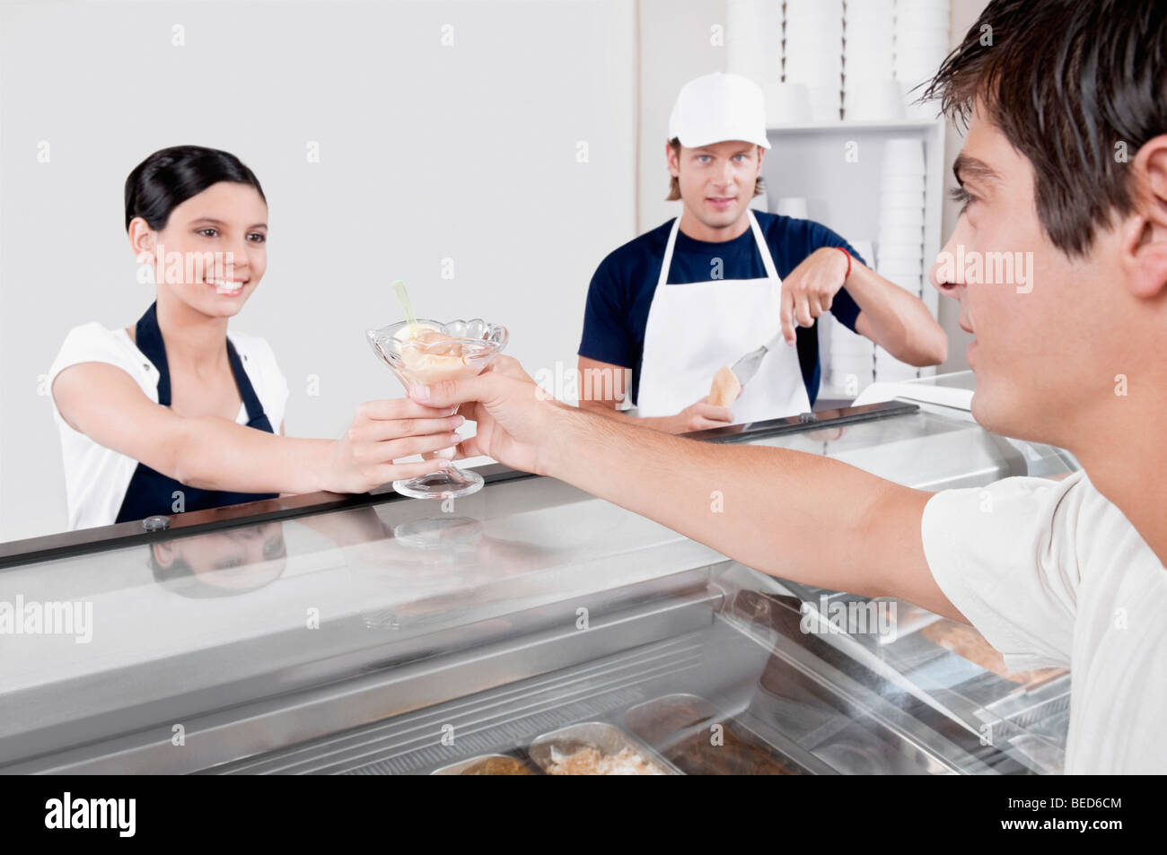 Female ice cream seller giving ice cream to a customer Stock Photo - Alamy