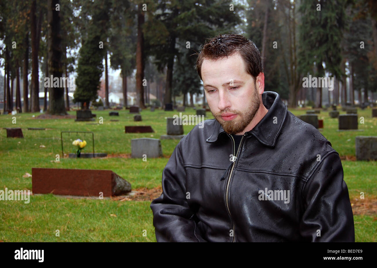 Sad man visiting cemetery on a rainy day Stock Photo - Alamy