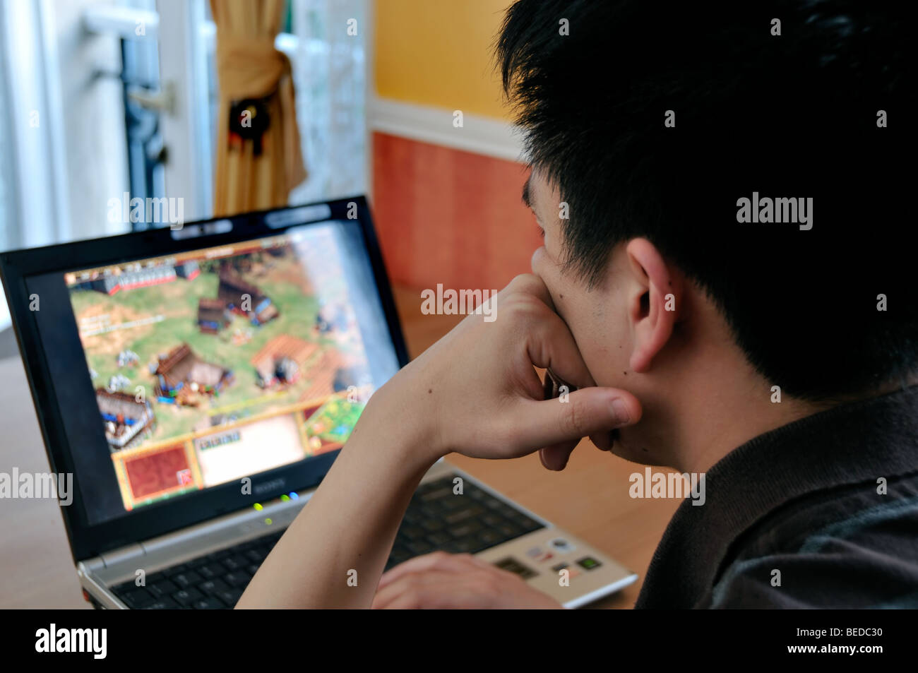 Young Asian Man Looking at Laptop Computer, Screen Over Shoulder, From ...