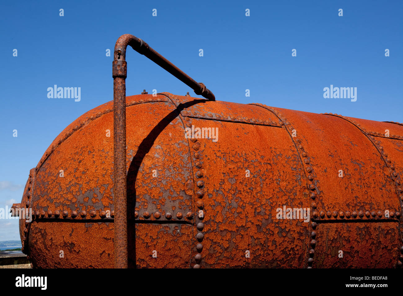 Rusting orange tank against a deep blue, cloudless sky Stock Photo - Alamy