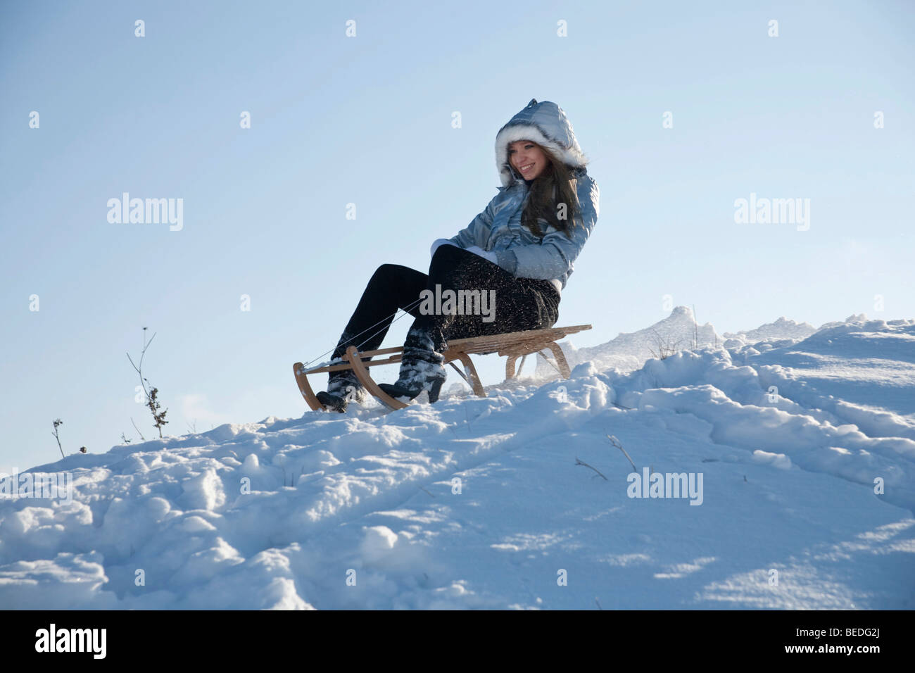 Young woman on a sledge in snow Stock Photo - Alamy