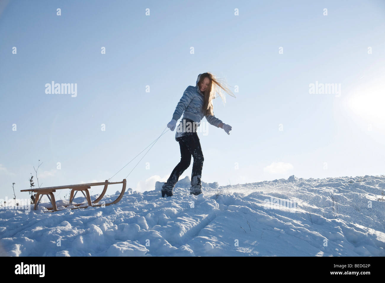 Young woman pulling a sledge in the snow Stock Photo - Alamy