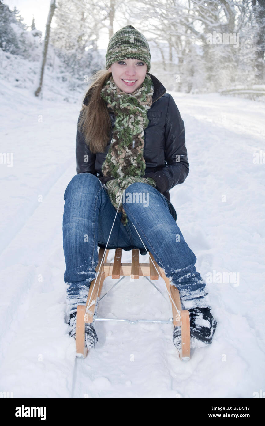 Young woman on a sledge in snow Stock Photo - Alamy