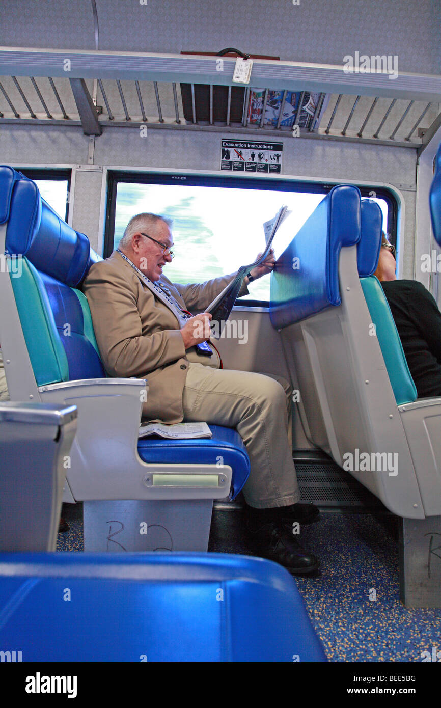 An elderly male commuter on a train, reading a newspaper Stock Photo ...