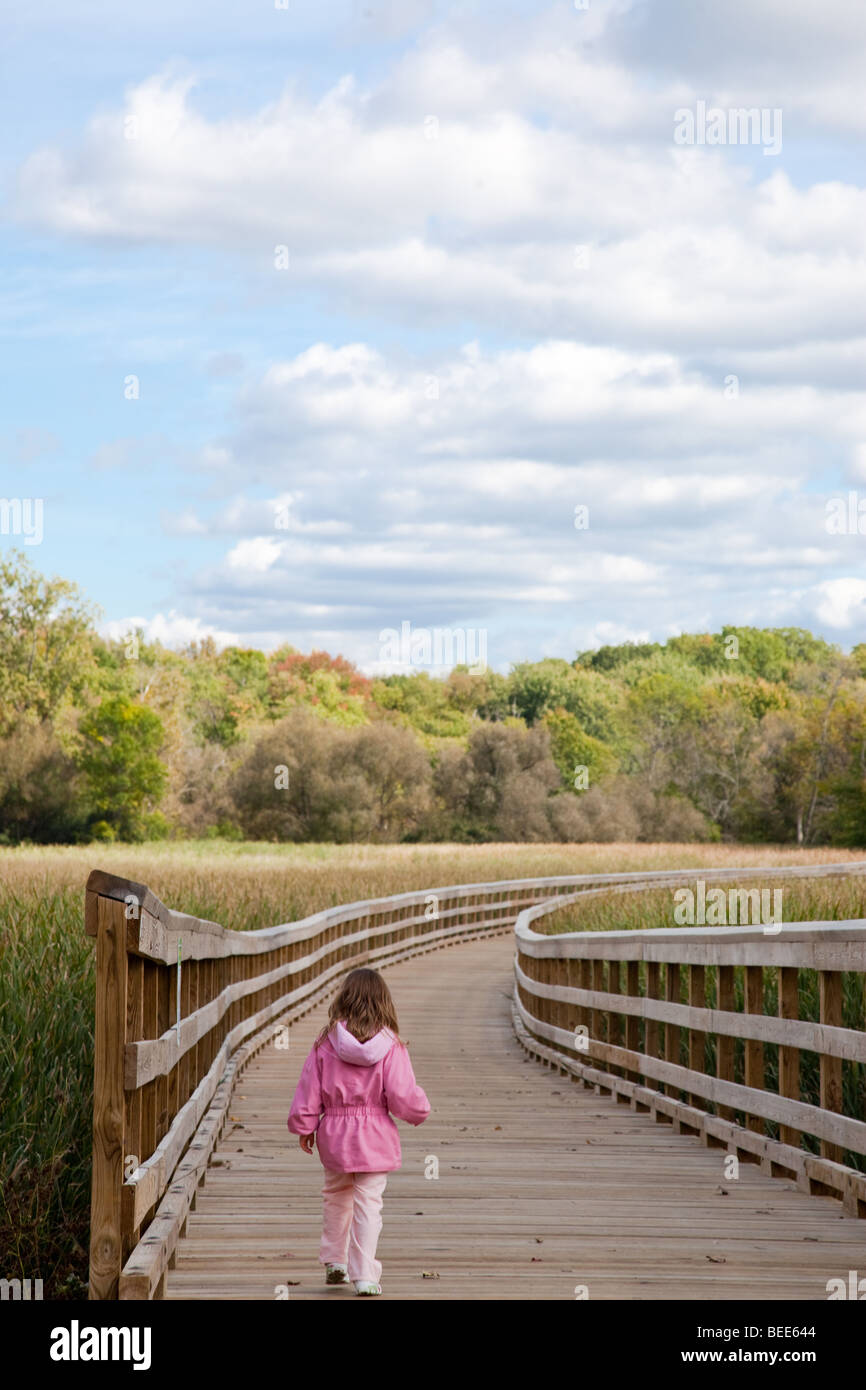 Little girl, age 4, starting a journey on a long, winding trail. She is ...