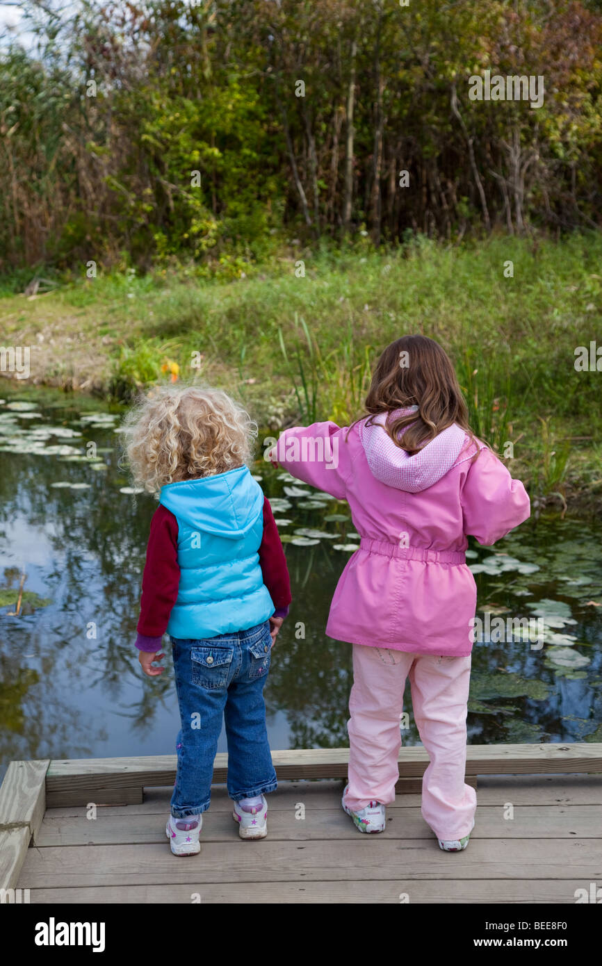 Two little girls of preschool age enjoying a pond in a local park Stock ...