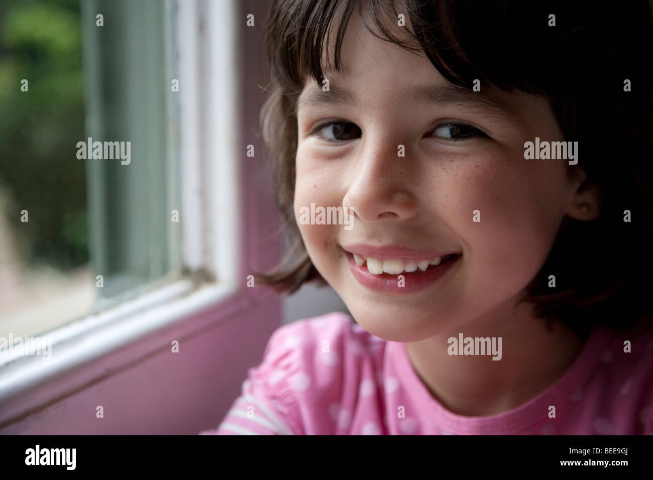 Little girl smiling by the window Stock Photo - Alamy