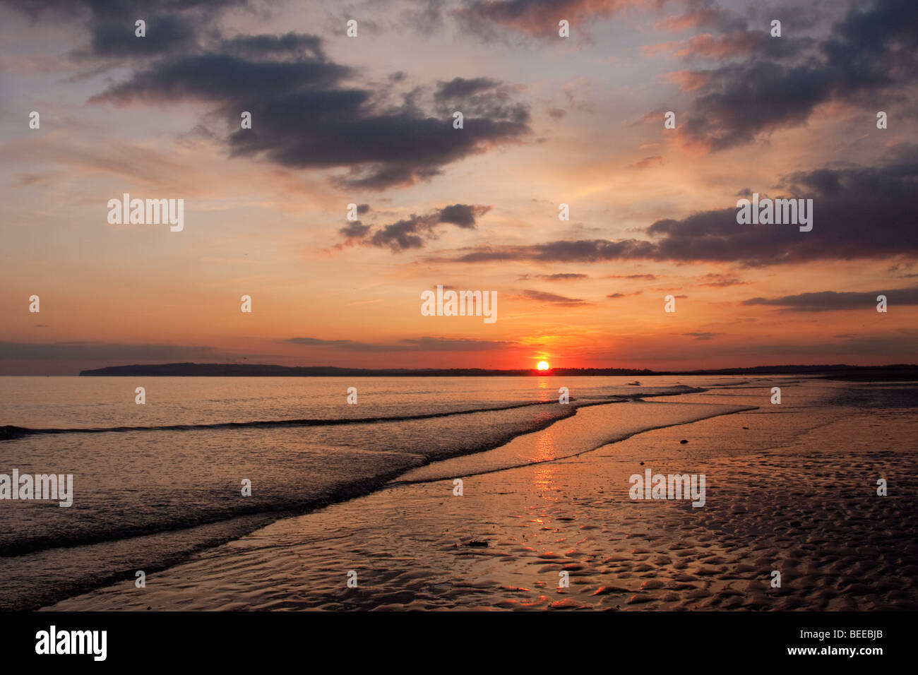 View of the sun setting over Camber Sands and the English Channel in ...