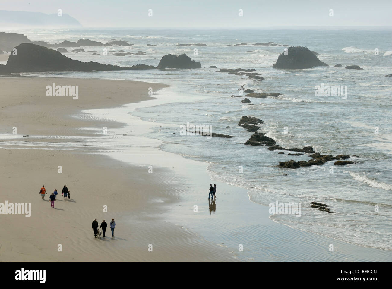 Pacific coast with people walking on a beach near Newport, backlighting ...