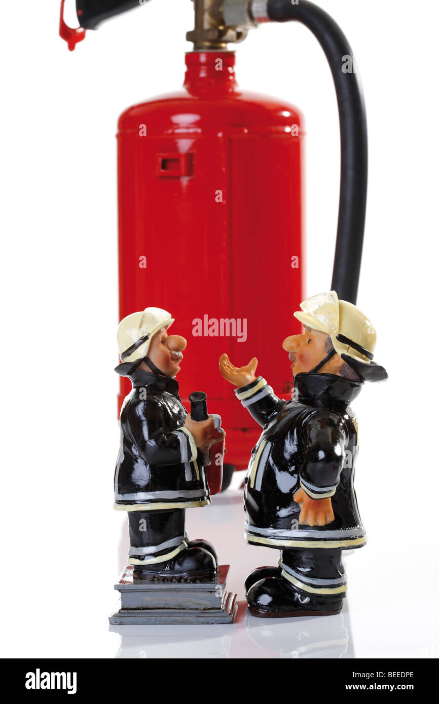 Miniature figures of fire fighters in front of a fire extinguisher ...
