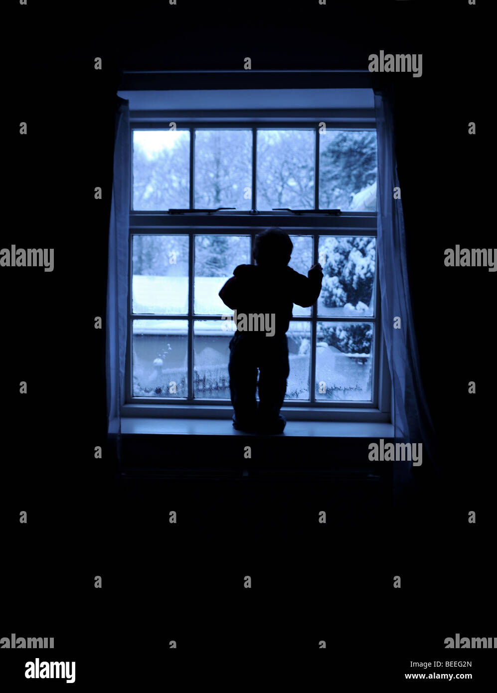 Boy in window looking at snow outside Stock Photo - Alamy