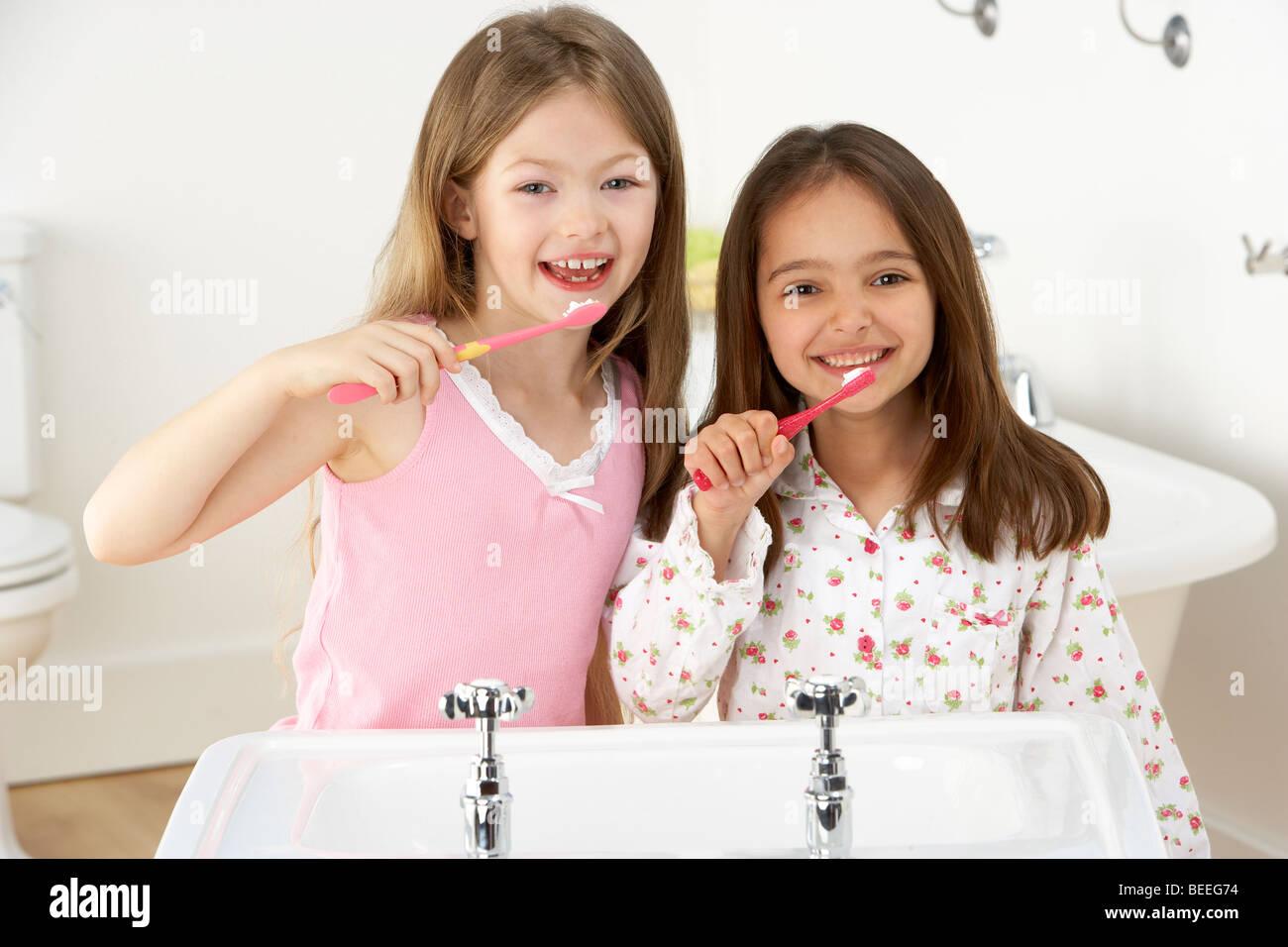 Two Young Girls Brushing Teeth at Sink Stock Photo - Alamy