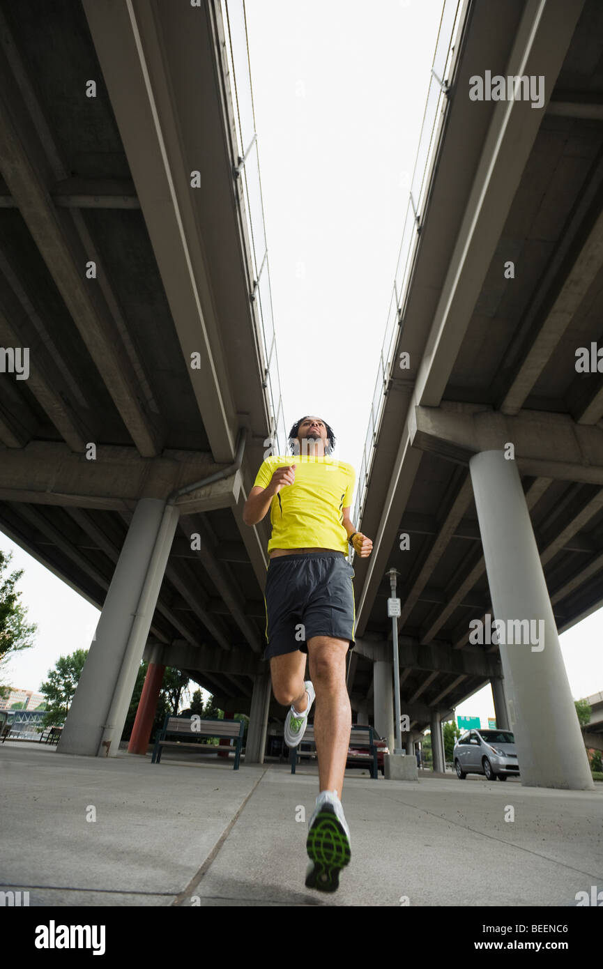 Mixed race man running under freeway overpass Stock Photo - Alamy