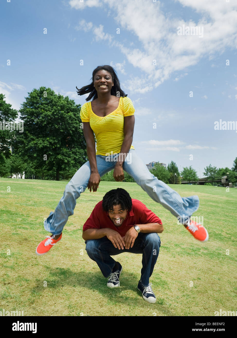 Woman leaping over man in park Stock Photo - Alamy