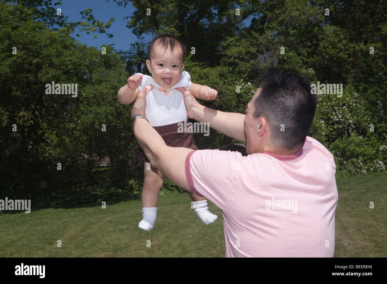 Chinese father lifting baby in park Stock Photo - Alamy