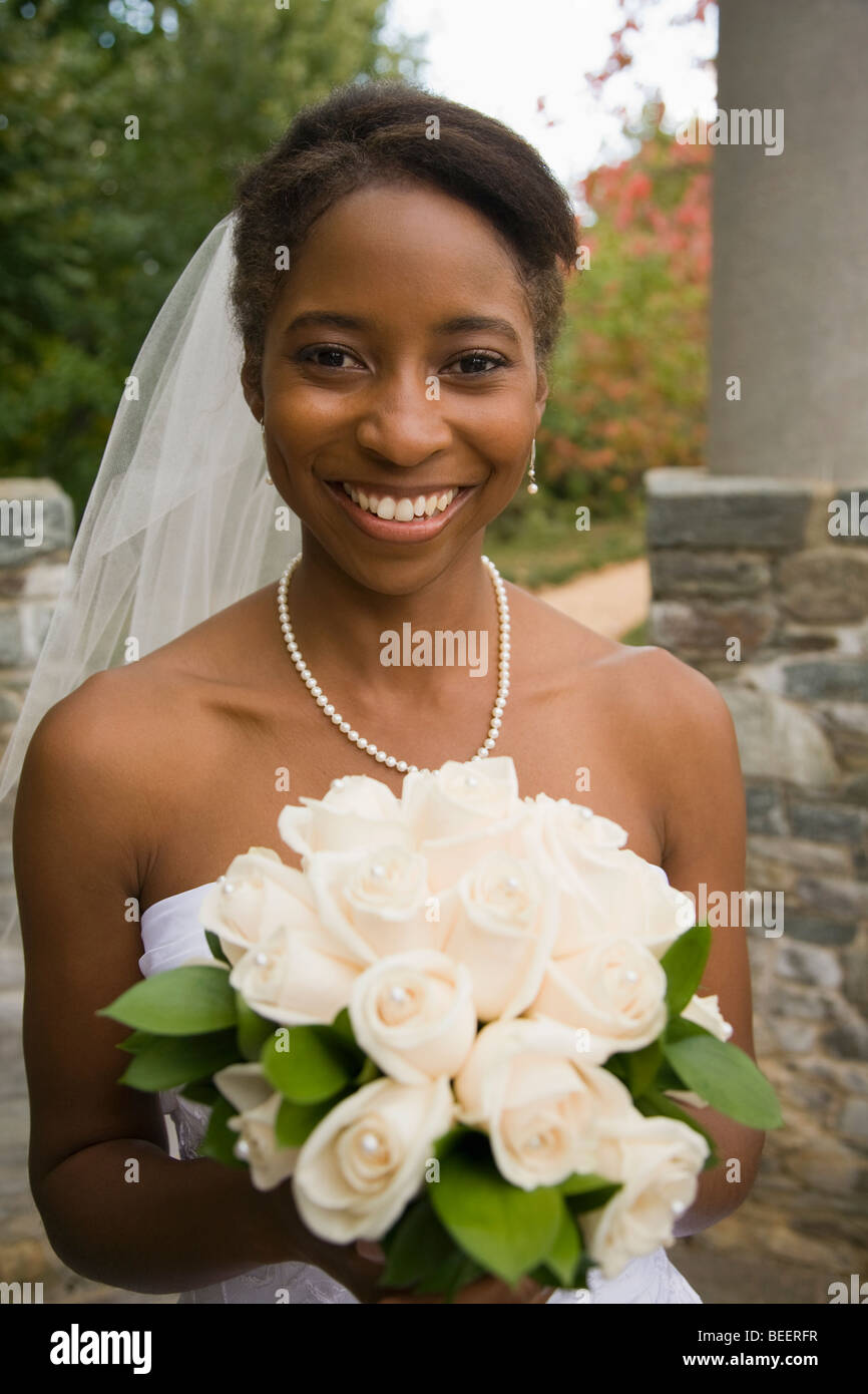 African bride holding rose bouquet and smiling Stock Photo - Alamy