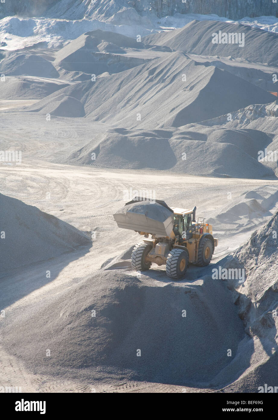 Aerial high-angle view of a front loader piling gravel at the bottom of ...