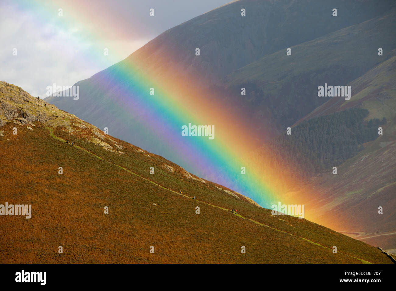 A rainbow arches over Steel Fell and walkers in the Lake District, UK ...