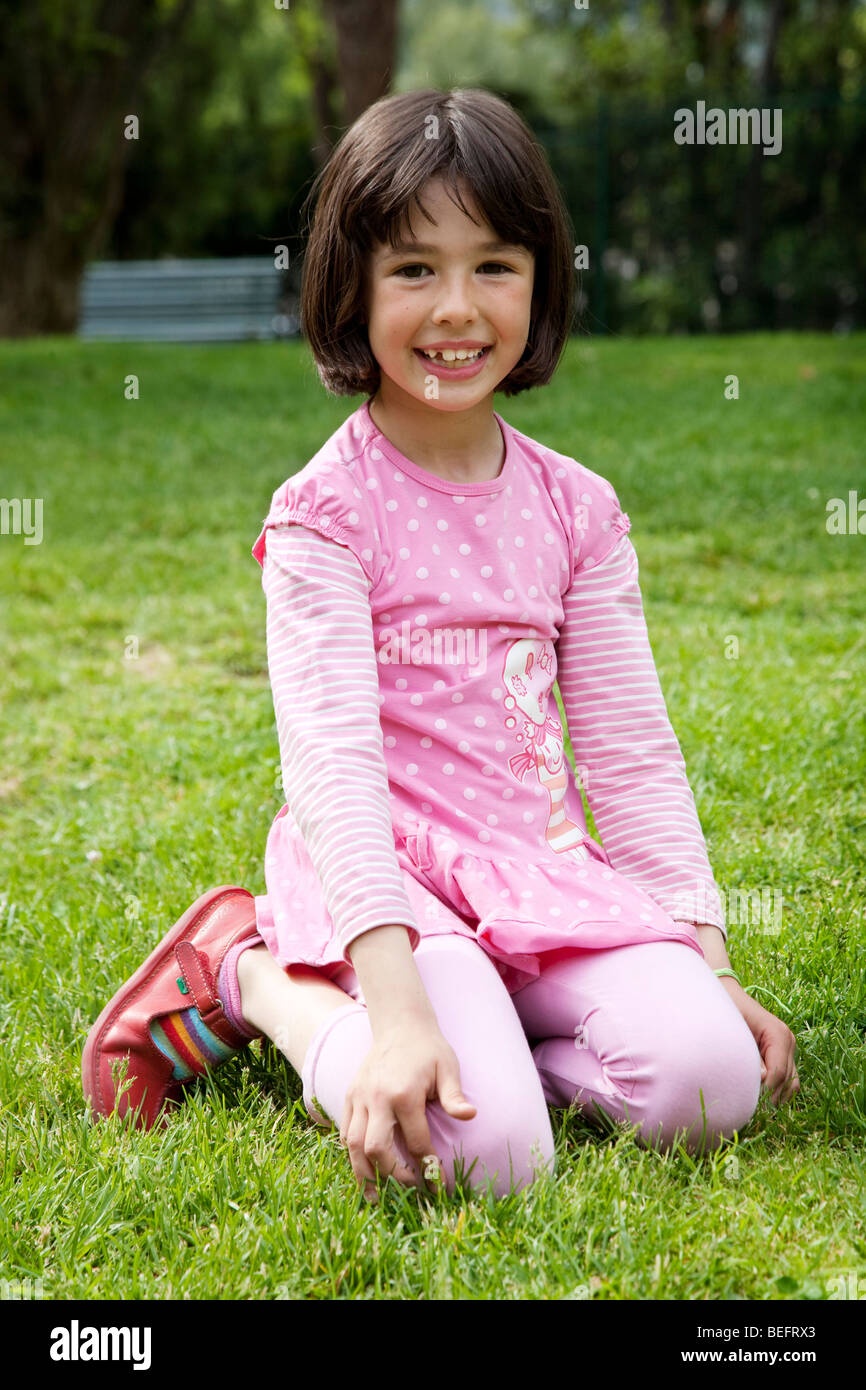 Little girl sitting on the grass in a park Stock Photo - Alamy