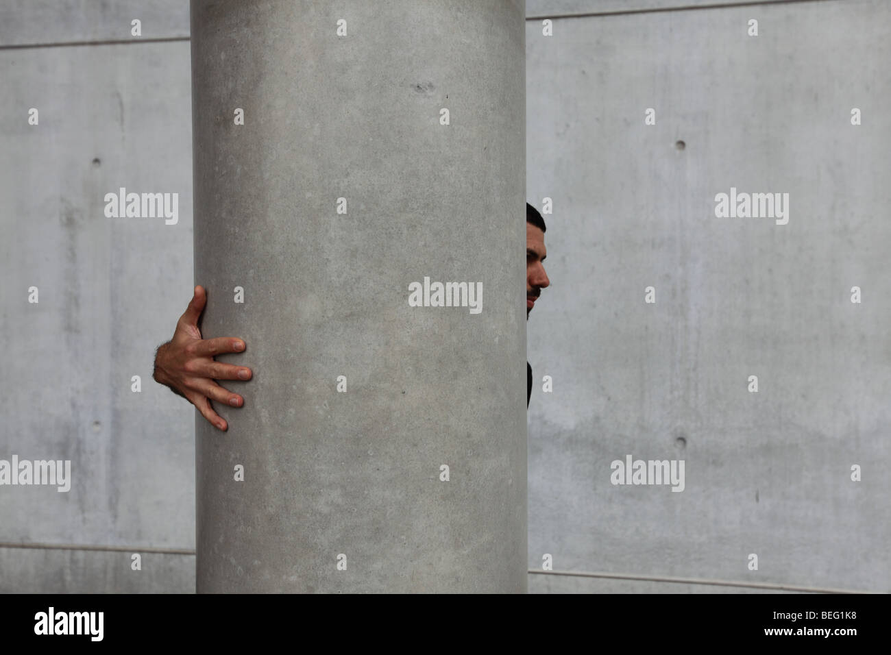 Person hiding behind Pillar revealing face and hand Stock Photo - Alamy