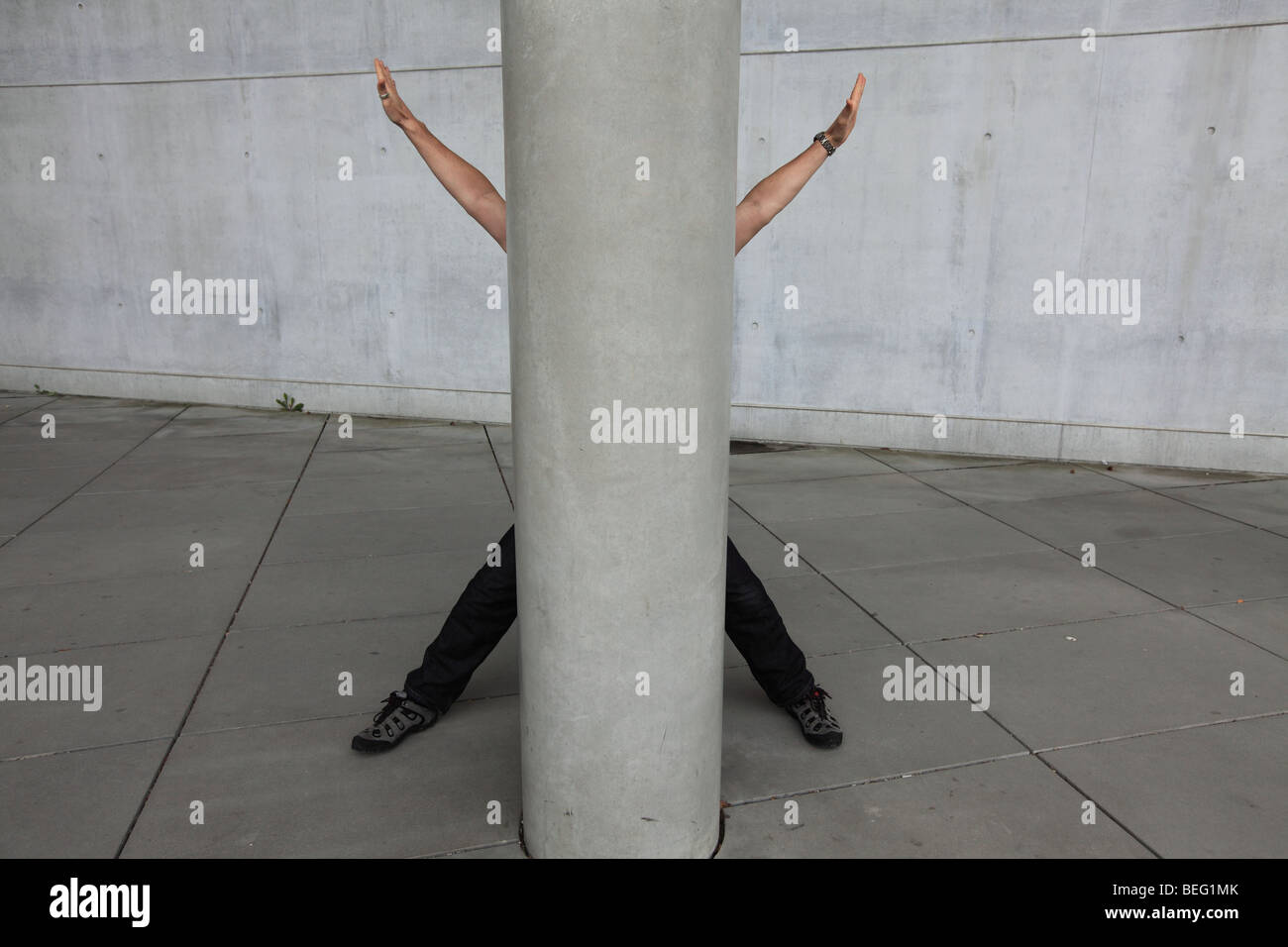 Person hiding behind Pillar revealing legs and arms Stock Photo - Alamy